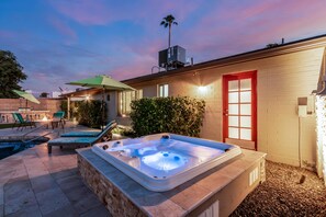 Um quintal com hidromassagem, área de estar externa e piscina.