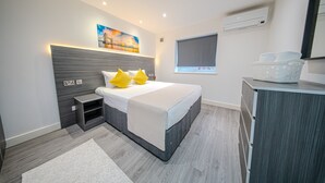 Um quarto moderno com cama, mesas de cabeceira, cômoda e um quadro na parede.