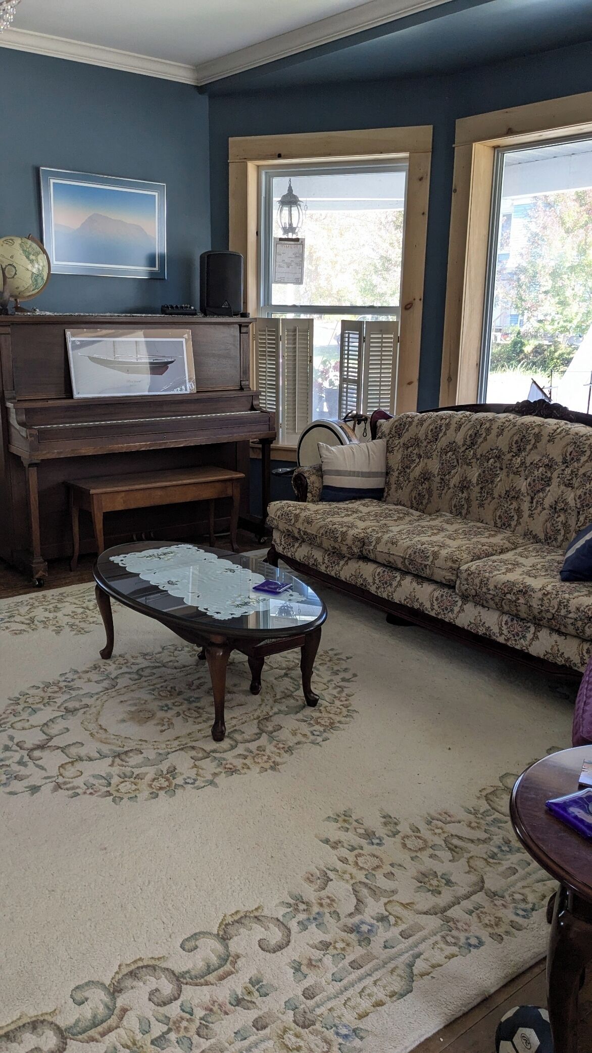 Uma sala de estar com piano, sofá, mesa de centro e tapete.