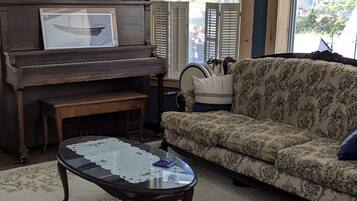 Uma sala de estar com piano, sofá, mesa de centro e tapete.