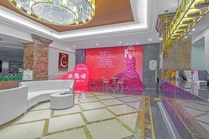 Um hall moderno com balcão de recepção, área de estar e uma parede decorativa.