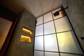 Um quarto com um painel deslizante shoji, uma pequena estante com garrafas e uma escada de madeira.