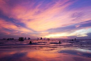 Uma cena de praia com barcos e pessoas.