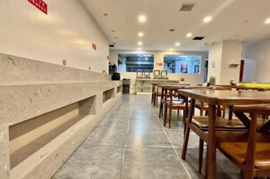 Interior de restaurante com um balcão comprido, mesas e cadeiras de madeira.