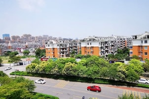 Zona residencial com edifícios de apartamentos e uma rua com veículos, sob um céu claro.