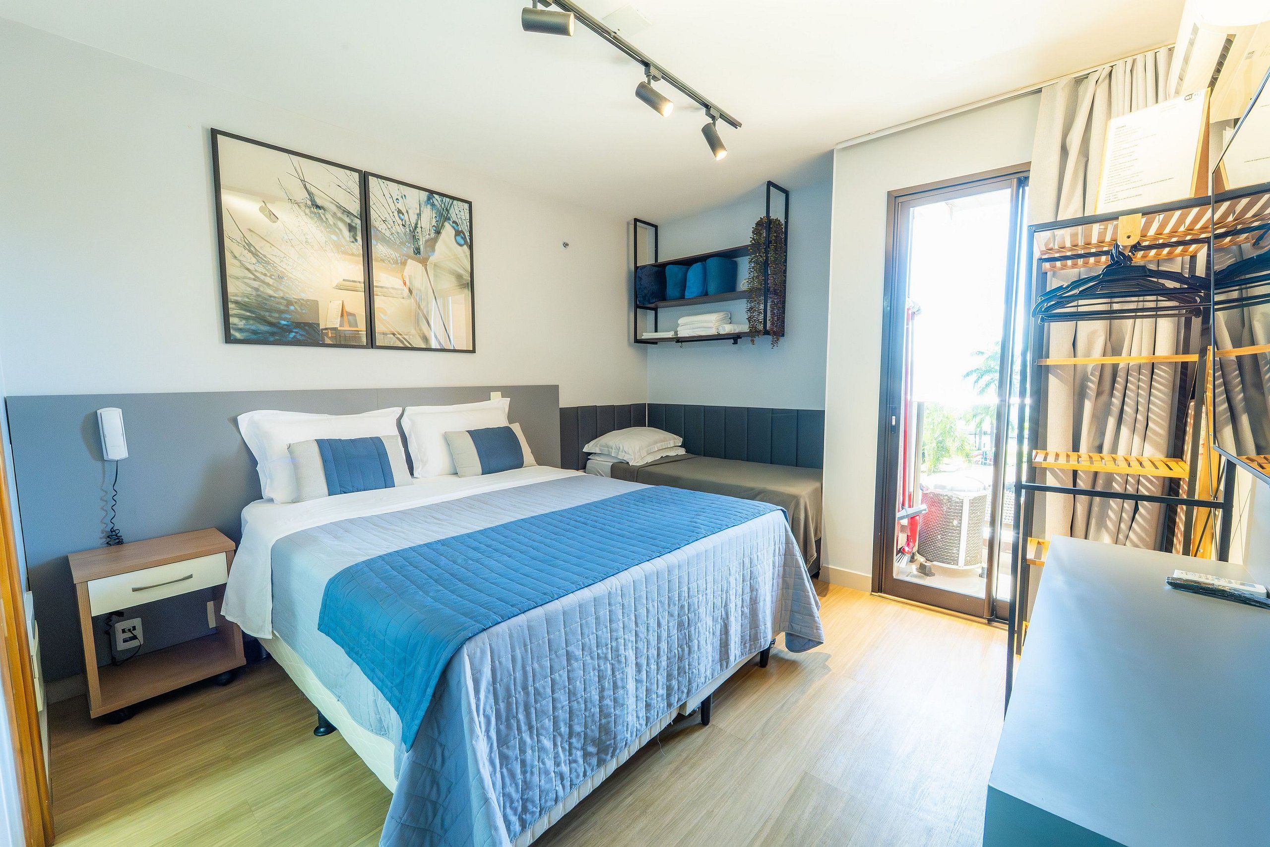 Quarto de hotel moderno com uma cama, mesa de cabeceira e janela com vista.