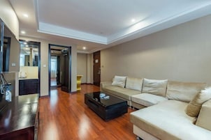 Uma sala de estar moderna com um sofá, mesa de centro e uma TV sobre um suporte.
