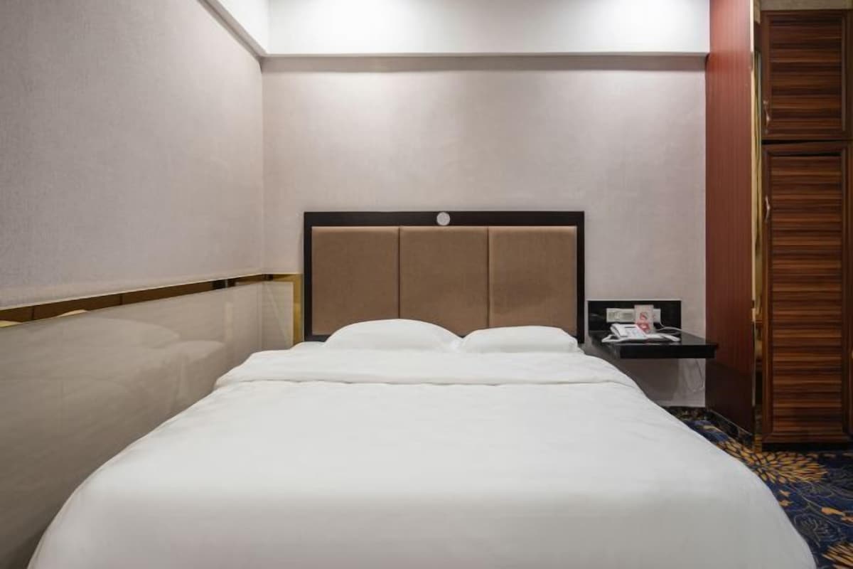 Quarto de hotel com cama, mesa de cabeceira e guarda-roupa.