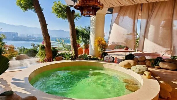 Uma banheira de hidromassagem com vista para um corpo d'água e montanhas ao fundo.