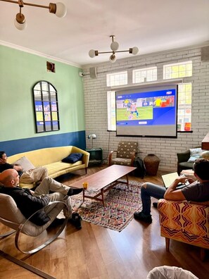 Uma sala de estar com televisão, sofá, mesa de centro e tapete estampado.