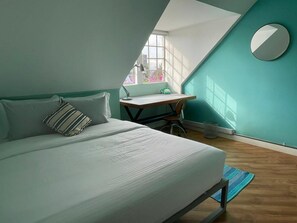 Um quarto com cama, escrivaninha, cadeira, janela e espelho.