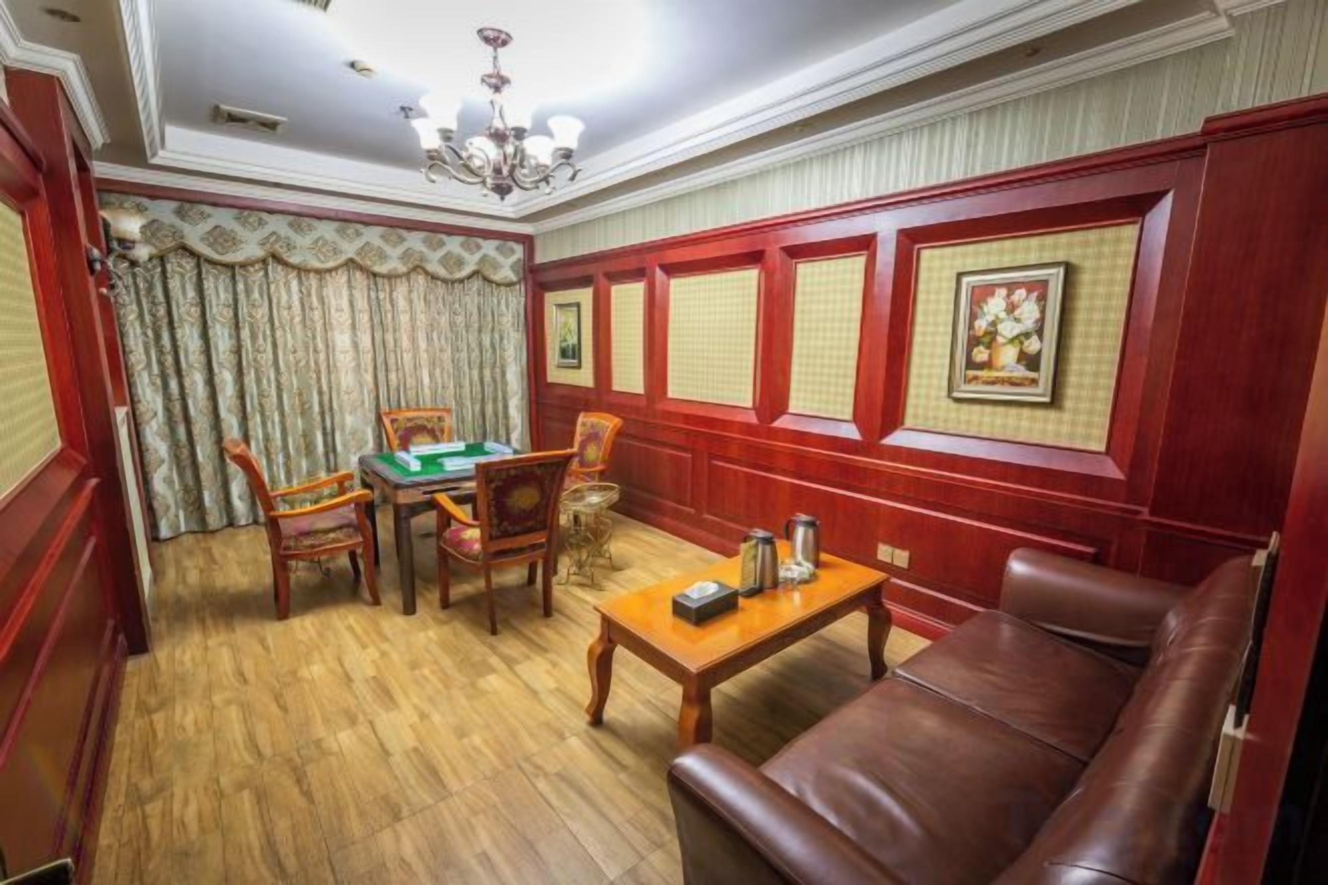 Um quarto com piso de madeira, sofá de couro marrom, mesa de centro de madeira e parede vermelha com painéis decorativos.