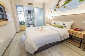 Quarto de hotel com cama, mesa de cabeceira e uma parede com arte inspirada em pandas.