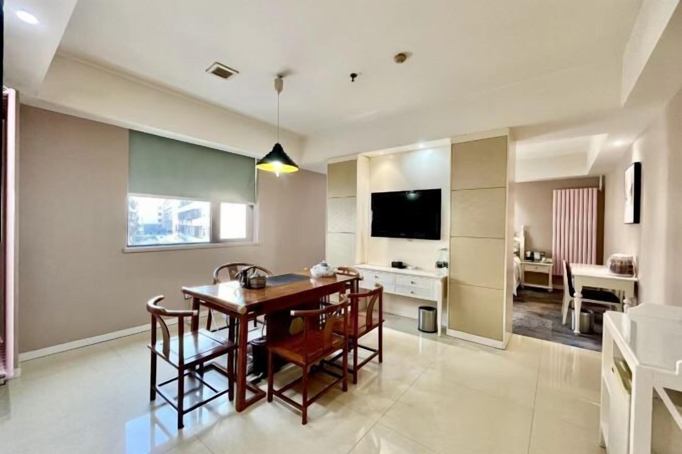 Uma cozinha moderna com mesa e cadeiras, TV fixada na parede e uma janela que oferece iluminação natural.