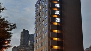 Um edifício de hotel moderno com letreiros iluminados, vários andares e uma entrada destacada.