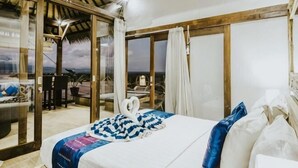 Um quarto com cama, vista através de uma porta de vidro e varanda com mesa e cadeiras.