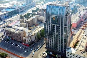 Um edifício alto com fachada de vidro moderna, cercado por outros edifícios e uma rua movimentada.
