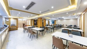 Uma sala de jantar ampla com várias mesas e cadeiras, um balcão com exposição de produtos e um teto com iluminação embutida.
