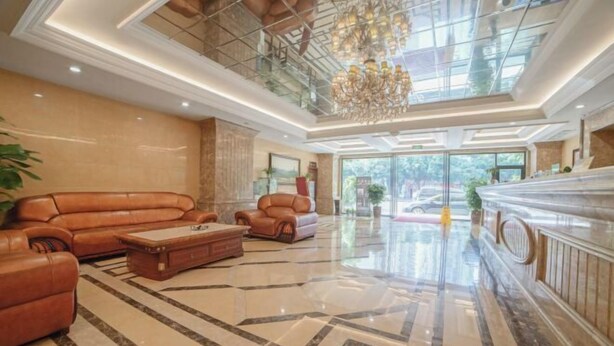 Um hall amplo com um sofá de couro, uma mesa de centro e um candelabro.