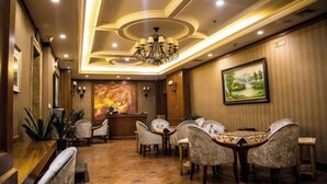Um saguão de hotel com balcão de recepção, área de estar e uma grande pintura na parede.
