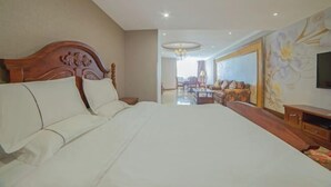 Quarto de hotel com uma cama grande, cabeceira de madeira, televisão e um mural floral na parede.