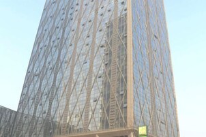 Um edifício alto com fachada geométrica marcante, apresentando um padrão de losangos e uma estrutura em grade.