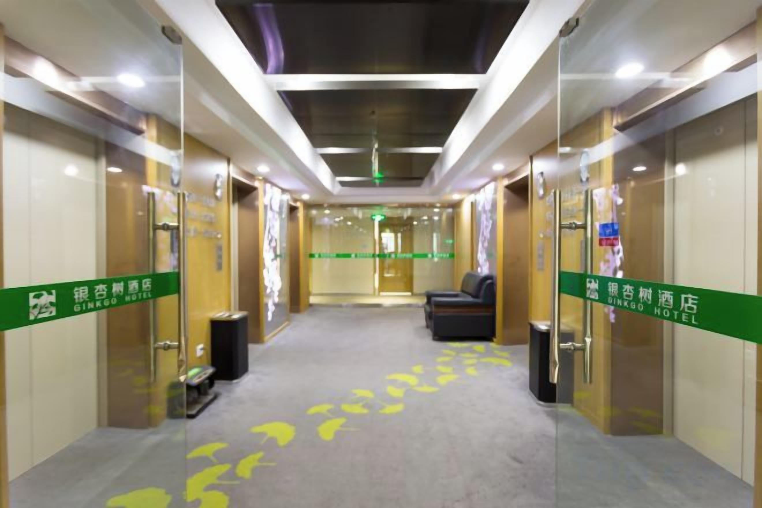 Corredor de hotel com piso revestido de carpete, balcão de recepção e área de estar.