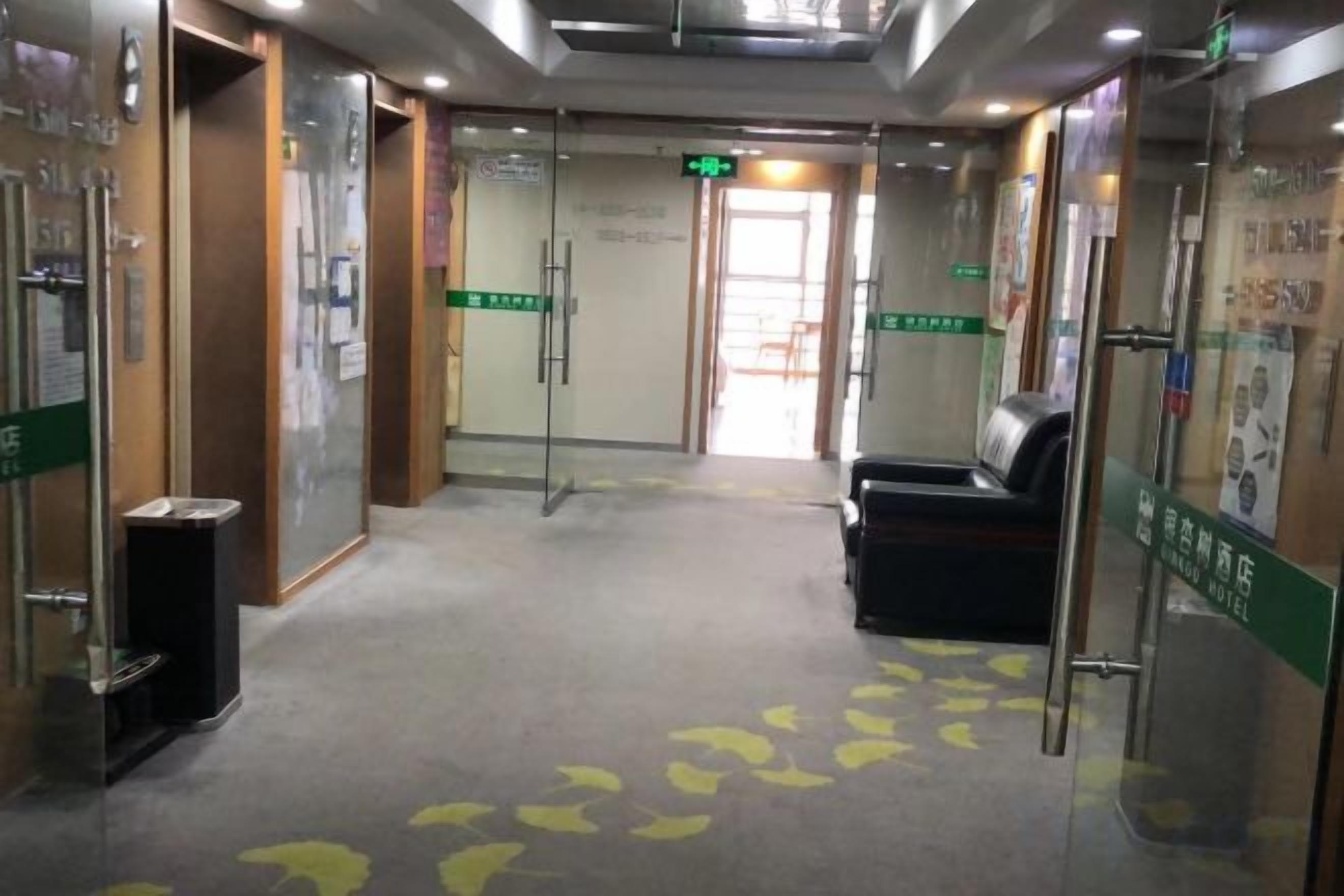 Um saguão de hotel com balcão de recepção, portas de vidro e carpete com padrão de folhas.