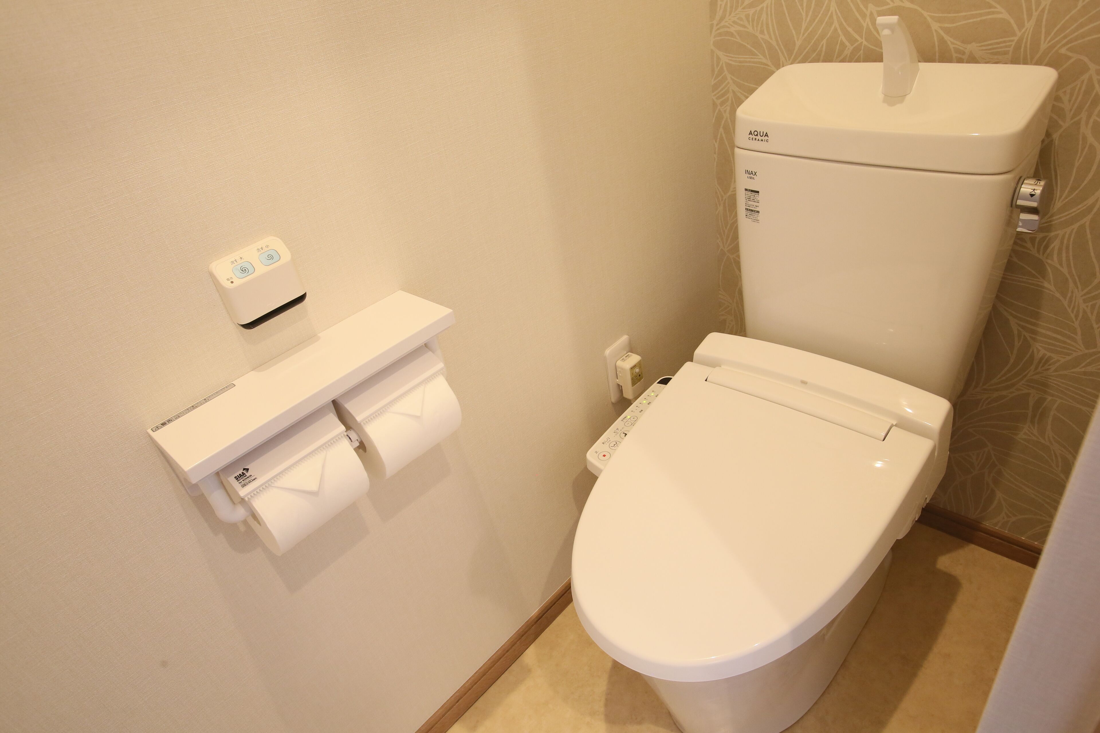 Um banheiro moderno com vaso sanitário, suporte para papel higiênico e aquecedor de água.