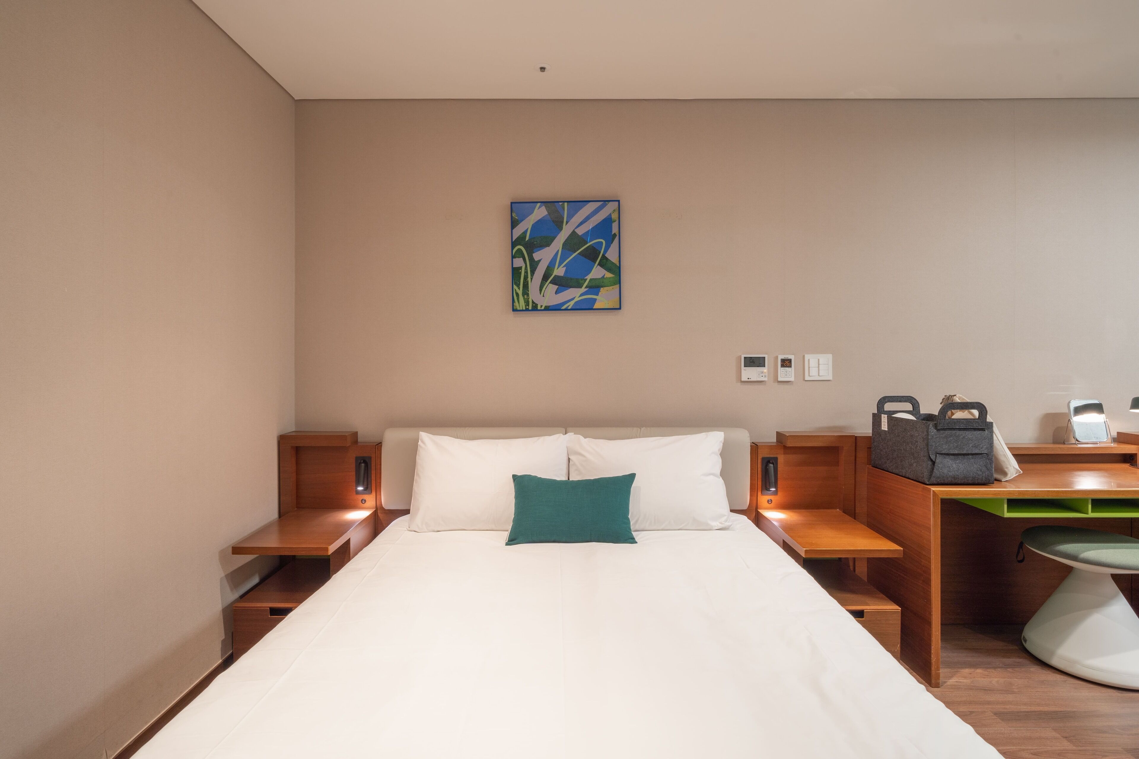 Quarto de hotel moderno com uma cama grande, mesas de cabeceira, uma escrivaninha e uma cadeira.