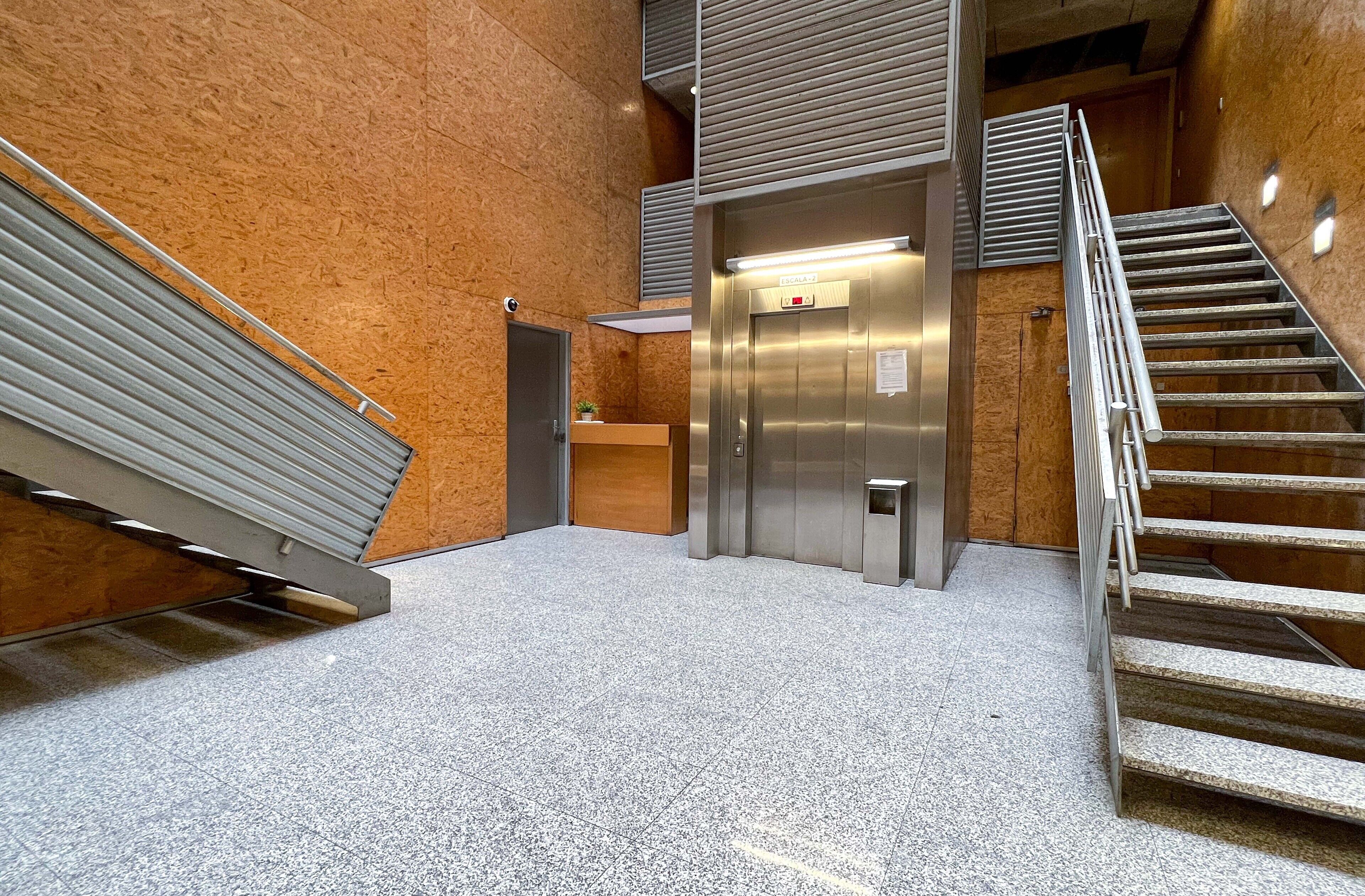 Interior com escada, elevador e balcão de recepção.