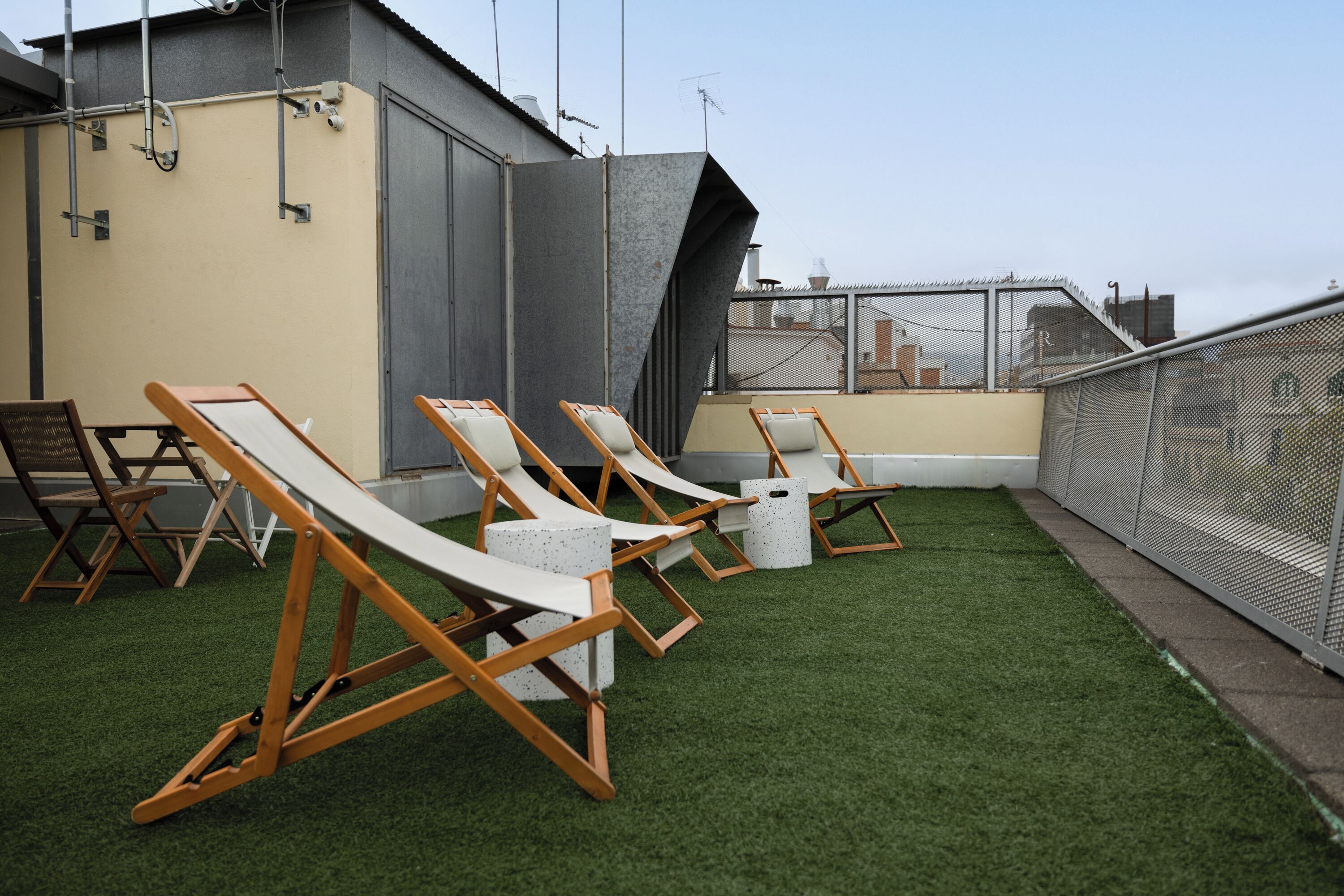 Terraço com cadeiras de estar e área gramada artificial.