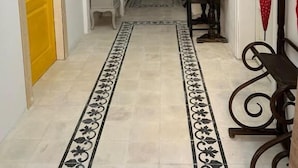 Um corredor com porta amarela, um espelho e uma mesa com um vaso.
