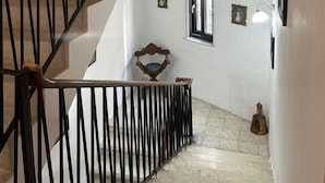 Uma escadaria com corrimão preto, um espelho decorativo e uma pequena janela com moldura.
