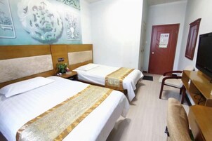 Quarto de hotel com duas camas, televisão, escrivaninha e uma cadeira.