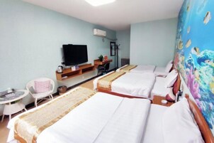 Quarto de hotel com duas camas, uma escrivaninha, uma cadeira e uma televisão.