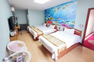 Quarto de hotel com duas camas, um mural com cena subaquática, uma área de refeições e um pequeno espaço de estar.
