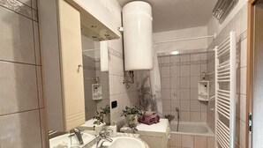 Uma casa de banho moderna com uma grande pia, espelho e banheira.