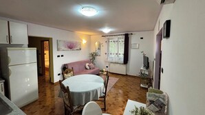 Um espaço compacto com cozinha americana, área de refeições e sala de estar com sofá e mesa.