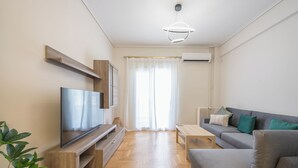 Uma sala de estar moderna com uma televisão de tela plana, móvel para entretenimento em madeira, sofá cinza e uma mesa de centro.