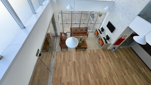 Um interior espaçoso com teto alto, piso de madeira e uma área de estar com um banco e cadeiras.