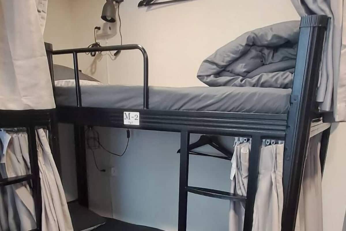 Quarto com beliche, escrivaninha, luminária e luminária pendente.