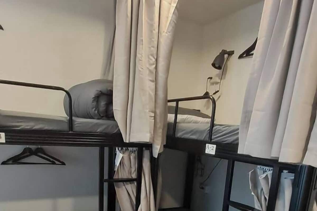 Quarto nos fundos com beliches, luminária no teto e abajur fixado na parede.