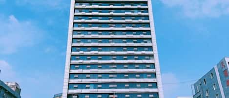 Um edifício de vários andares com design arquitetônico moderno, apresentando uma série de janelas e um telhado plano.
