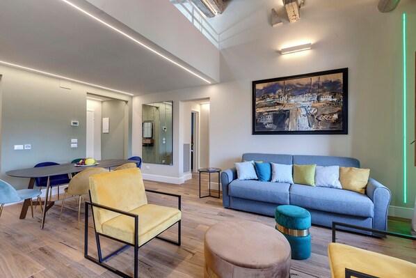 Uma sala de estar moderna com área de jantar, um sofá e um quadro na parede.