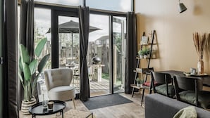 Uma sala de estar moderna com um sofá, uma mesa de jantar e uma grande porta de vidro deslizante que dá para um pátio externo.