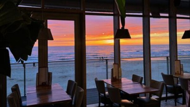 Um restaurante com vista para o oceano ao pôr do sol.