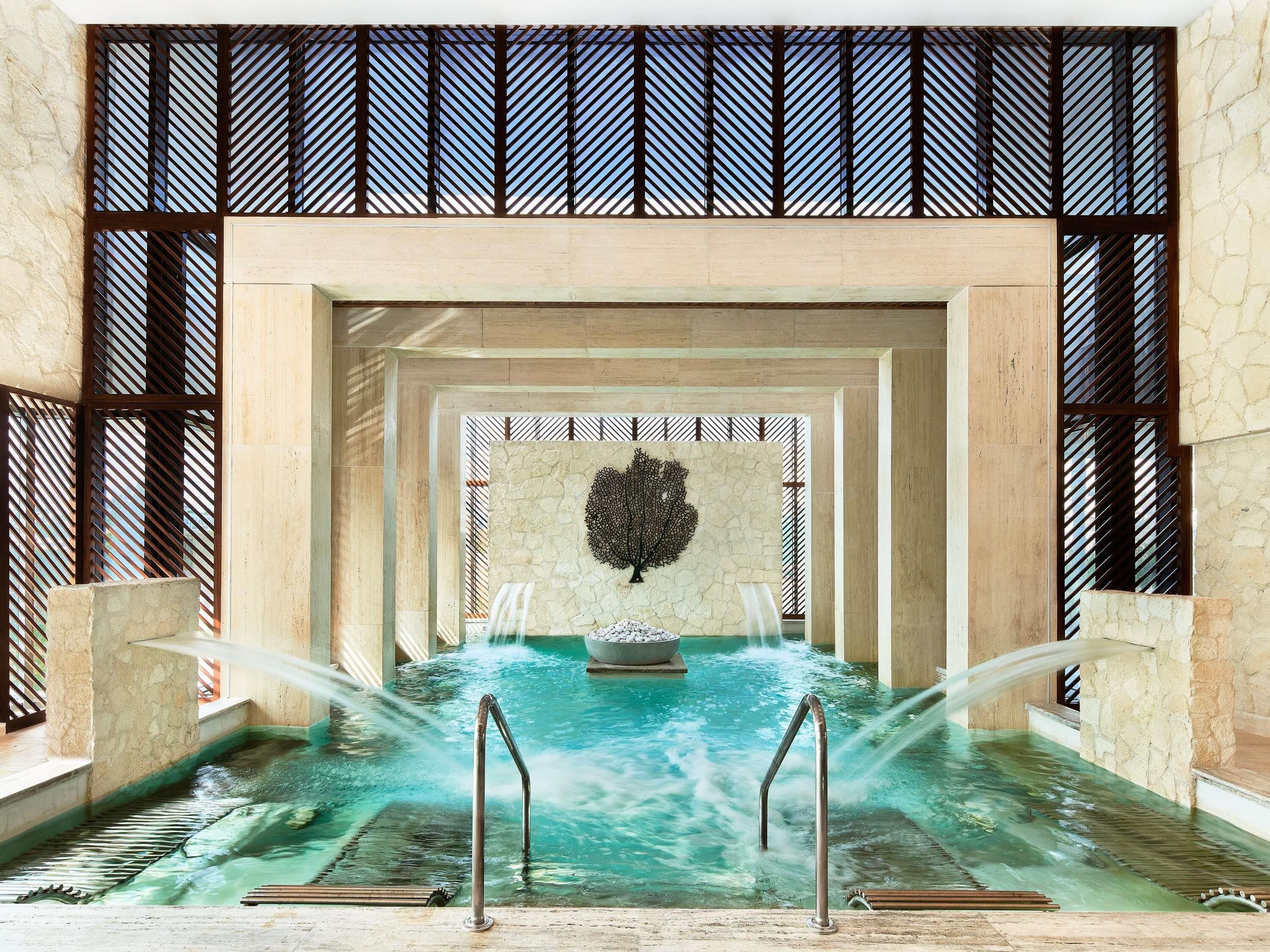 Uma área de spa com parede de pedra, elemento aquático e guarda-corpo de metal.
