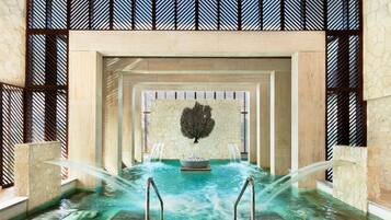 Uma área de spa com parede de pedra, elemento aquático e guarda-corpo de metal.