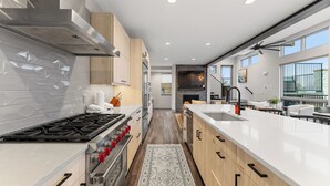 Uma cozinha moderna com uma ilha central, eletrodomésticos de aço inoxidável e vista para a sala de estar.